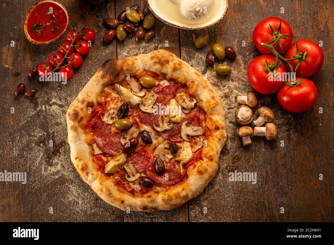Pizza on a wood table with ingredients Stock Photo - Alamy