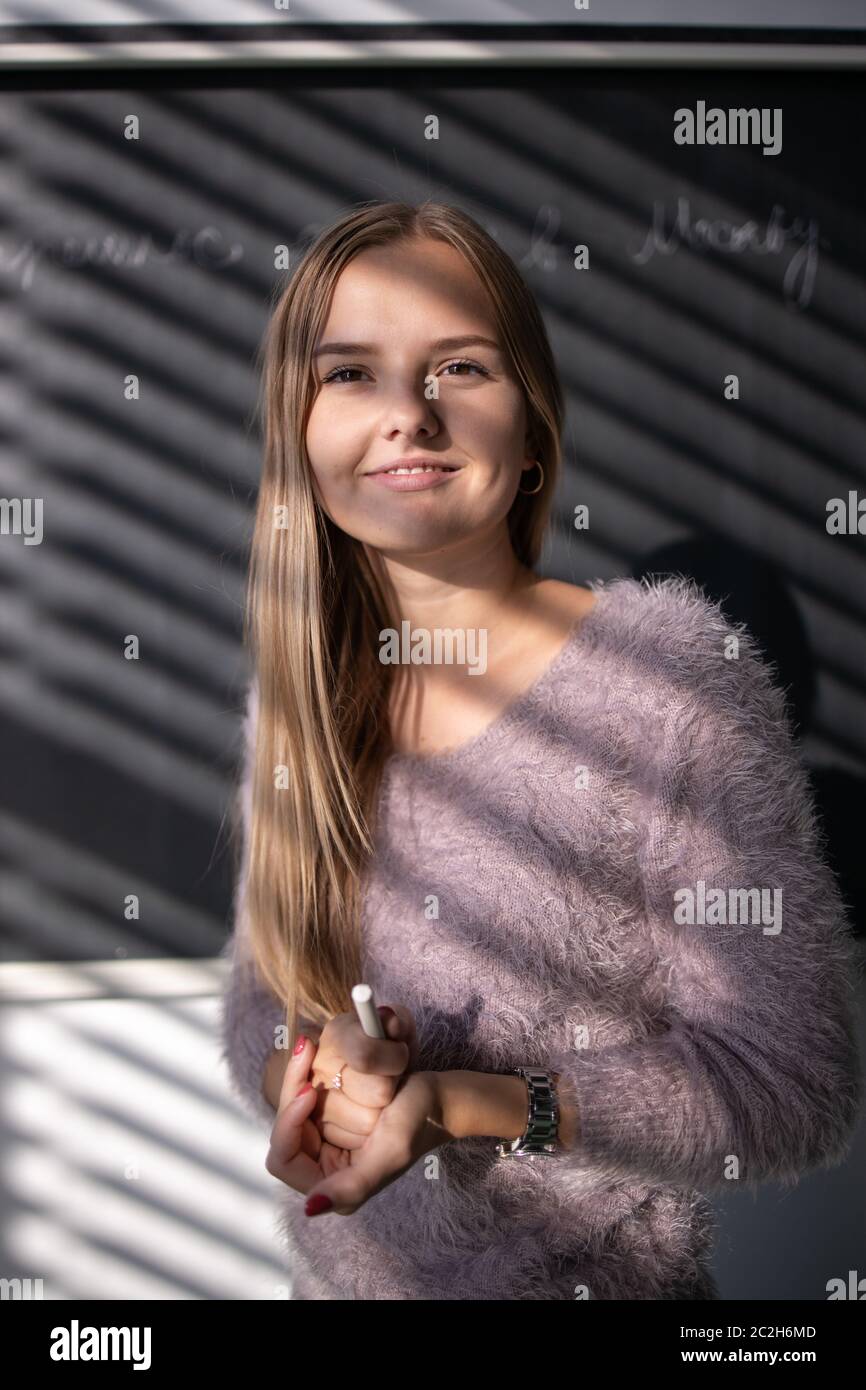 Pretty, young female student/teacher in front of a blackboard during ...
