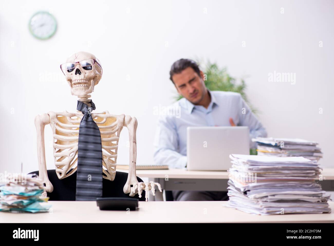 Young employee and skeleton in the office Stock Photo - Alamy