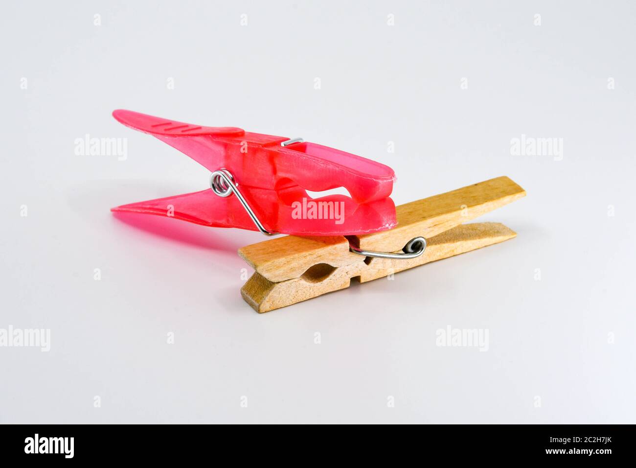 A traditional wooden clothes peg and a plastic clothes peg isolated on ...