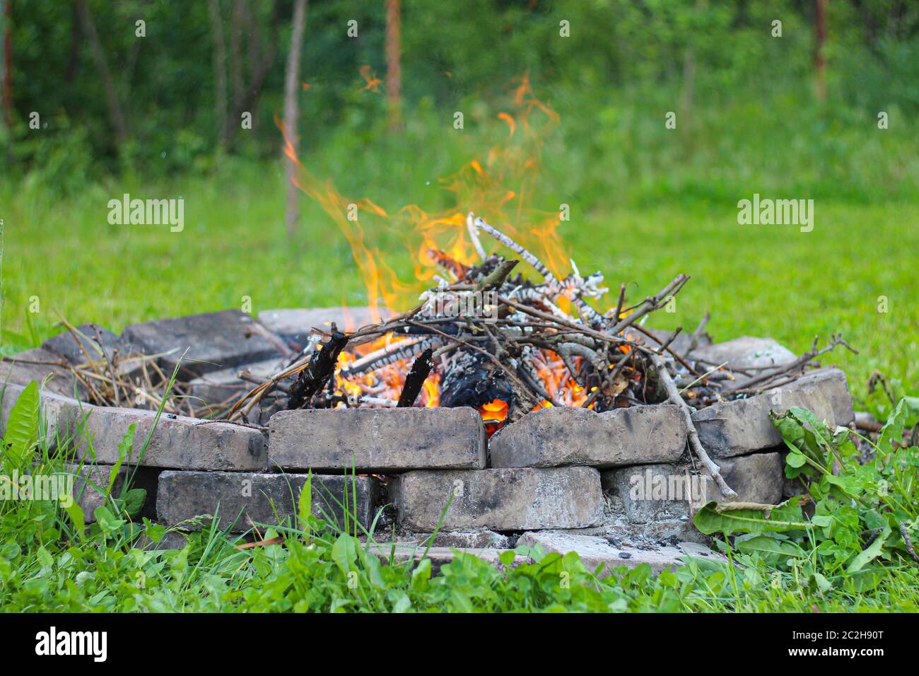 Refractory brick campfire in focus and blurred bonfire green grass in ...