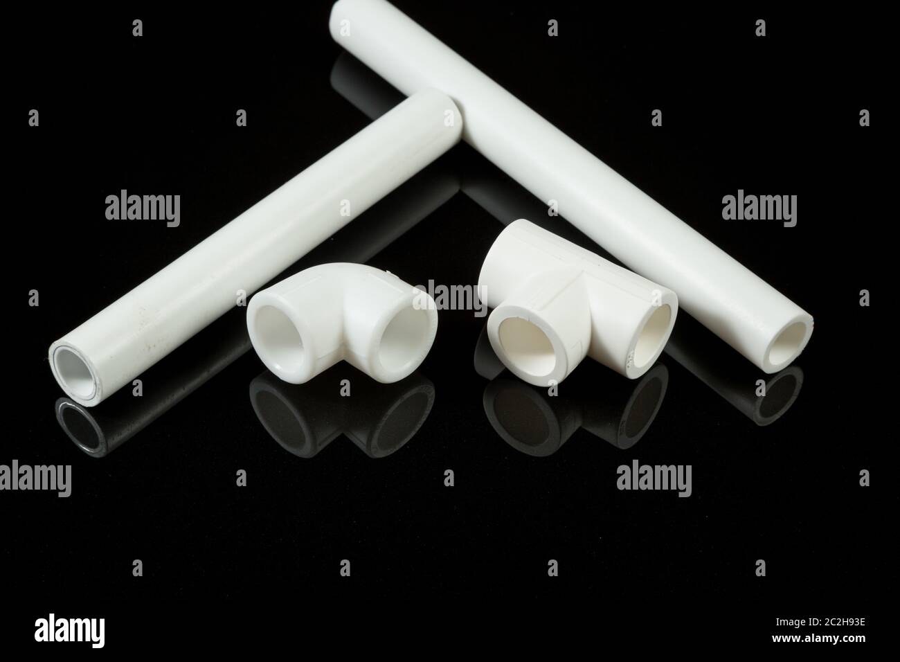 plastic pipe fittings on black isolated background, on black glass ...