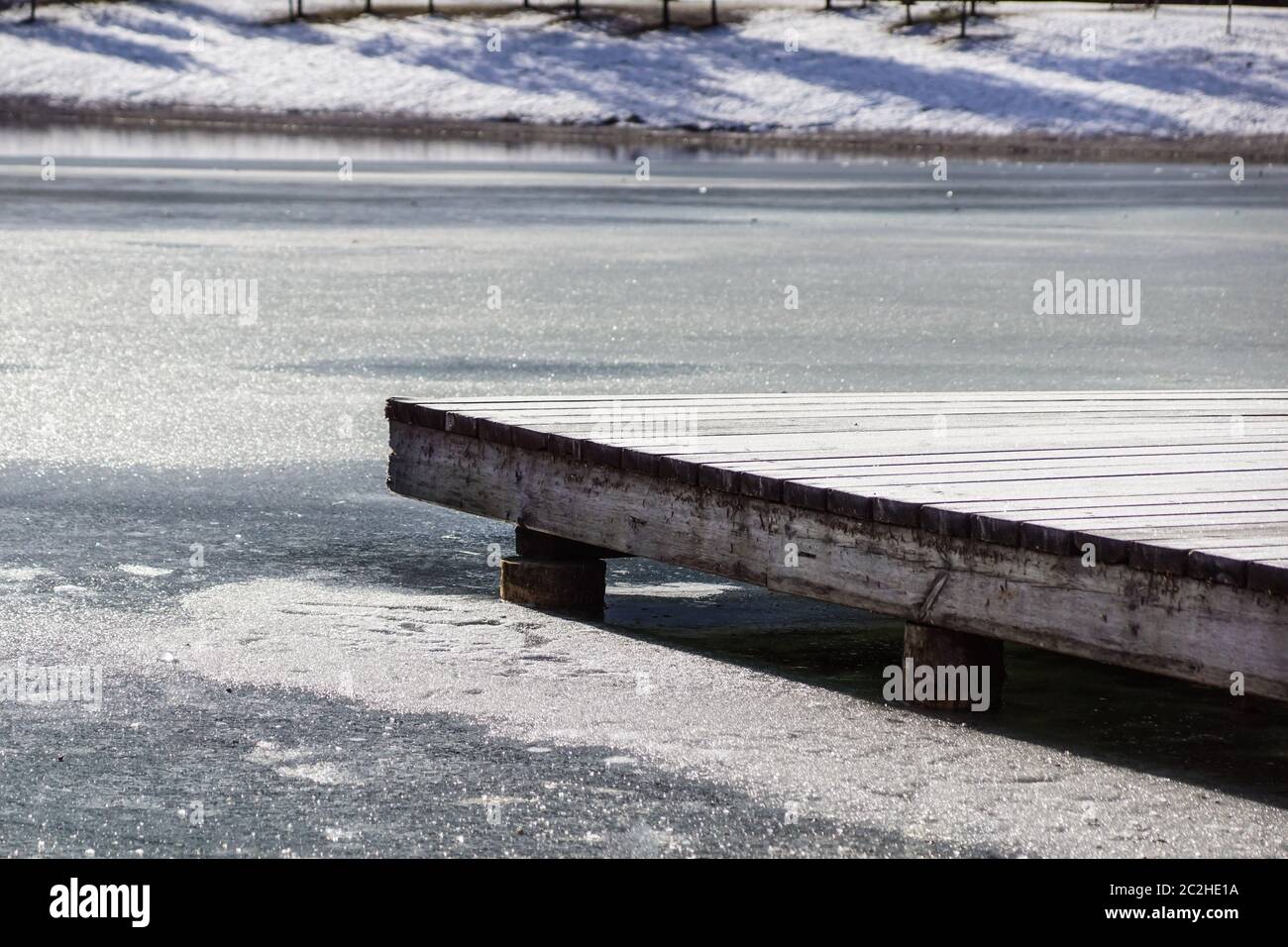 Mole pier on the lake. Wooden bridge in forest in winter time with blue ...