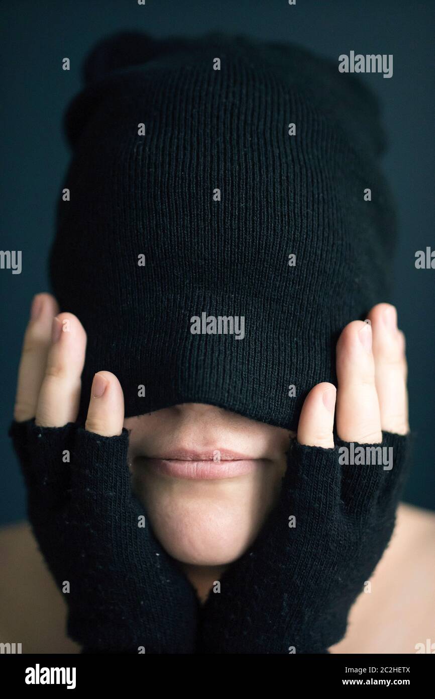 Unrecognizable girl in a black hat, pulled over her eyes and in gloves ...