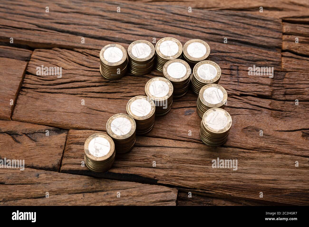 Stacked Coins Forming Arrow Sign On Wooden Desk Stock Photo - Alamy