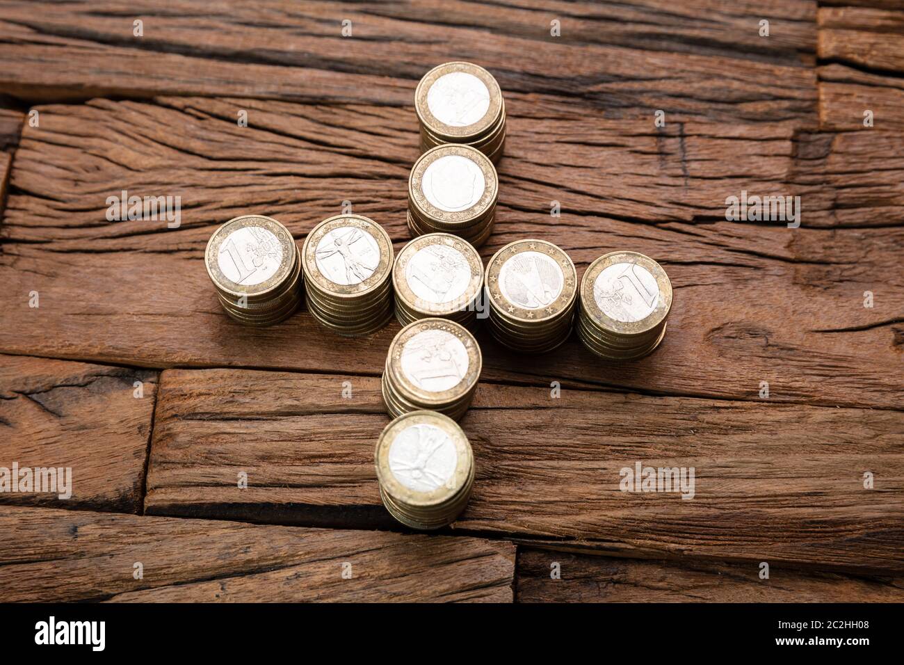 Stacked Coins Forming Plus Sign On Wooden Desk Stock Photo - Alamy
