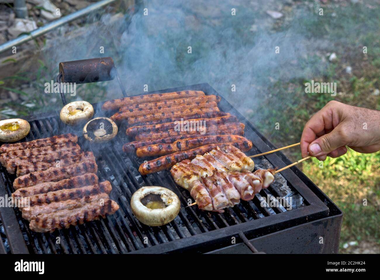 Preparing barbecue meat at picnic in nature. The meat is roasted in a ...