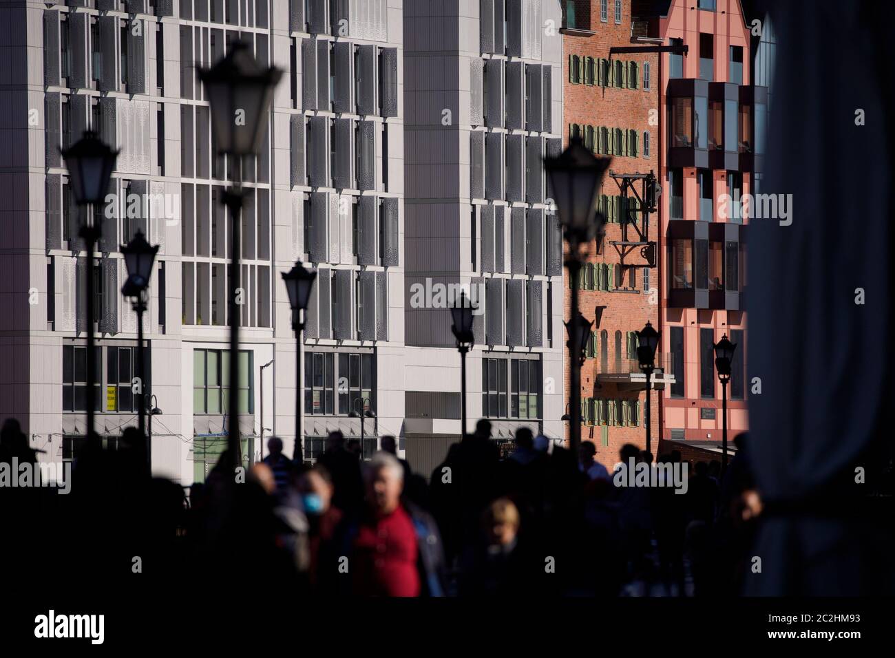 People are seen in the city center with modern buildings resembling the ...