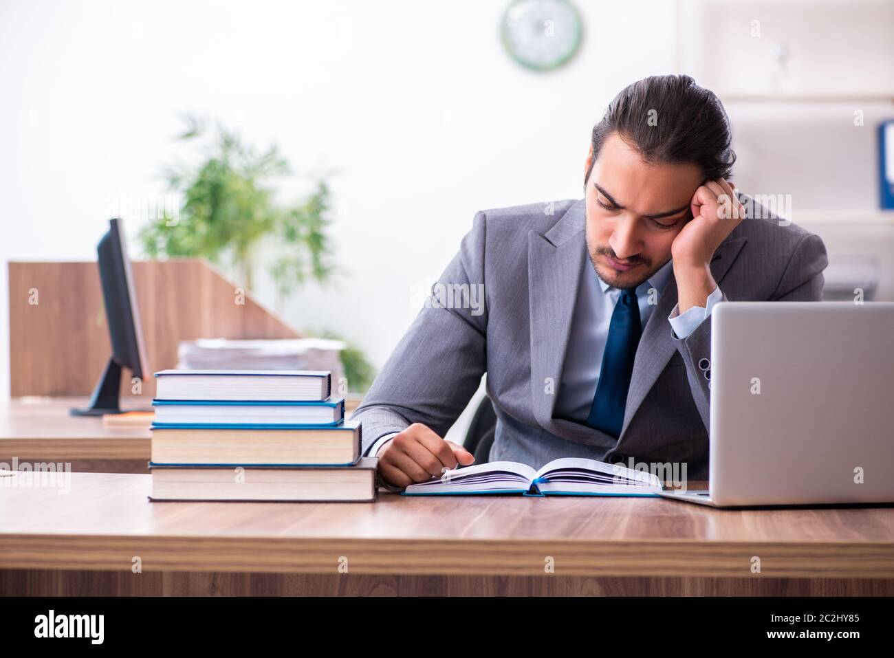 Young businessman reading books at workplace Stock Photo - Alamy