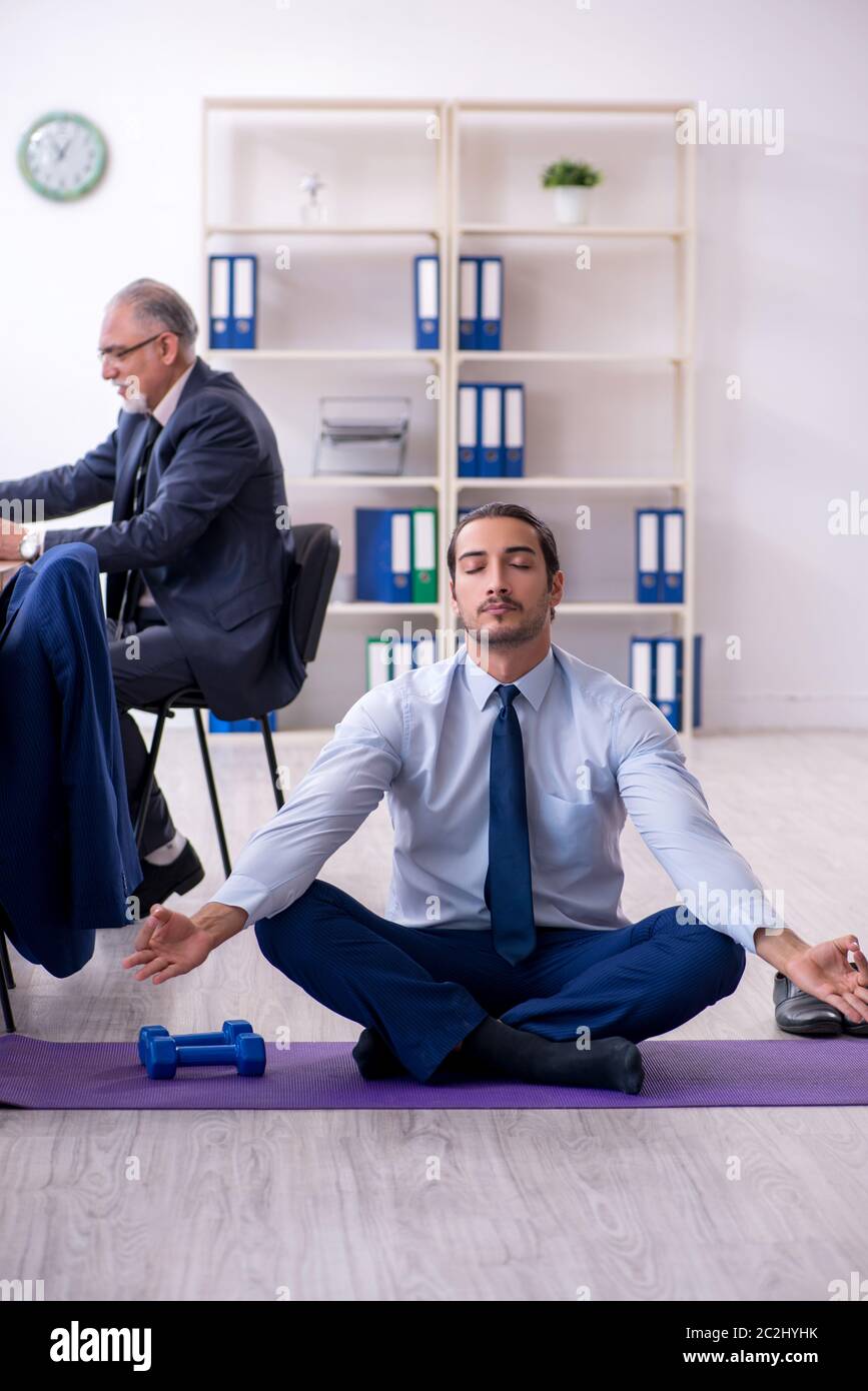 Two employees doing physical exercises at the workplace Stock Photo - Alamy