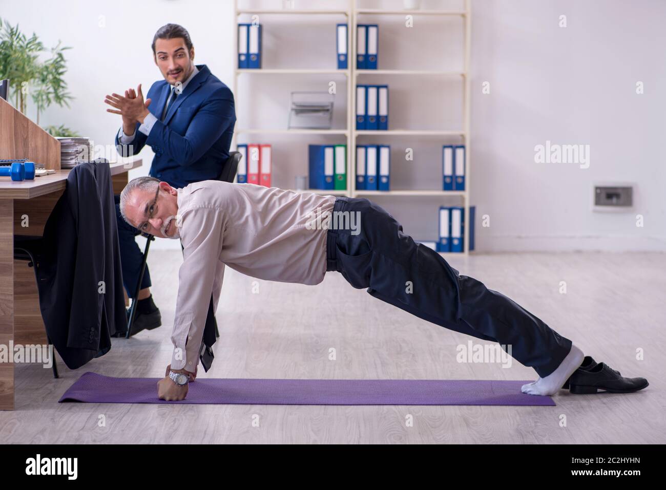 Two employees doing physical exercises at the workplace Stock Photo - Alamy