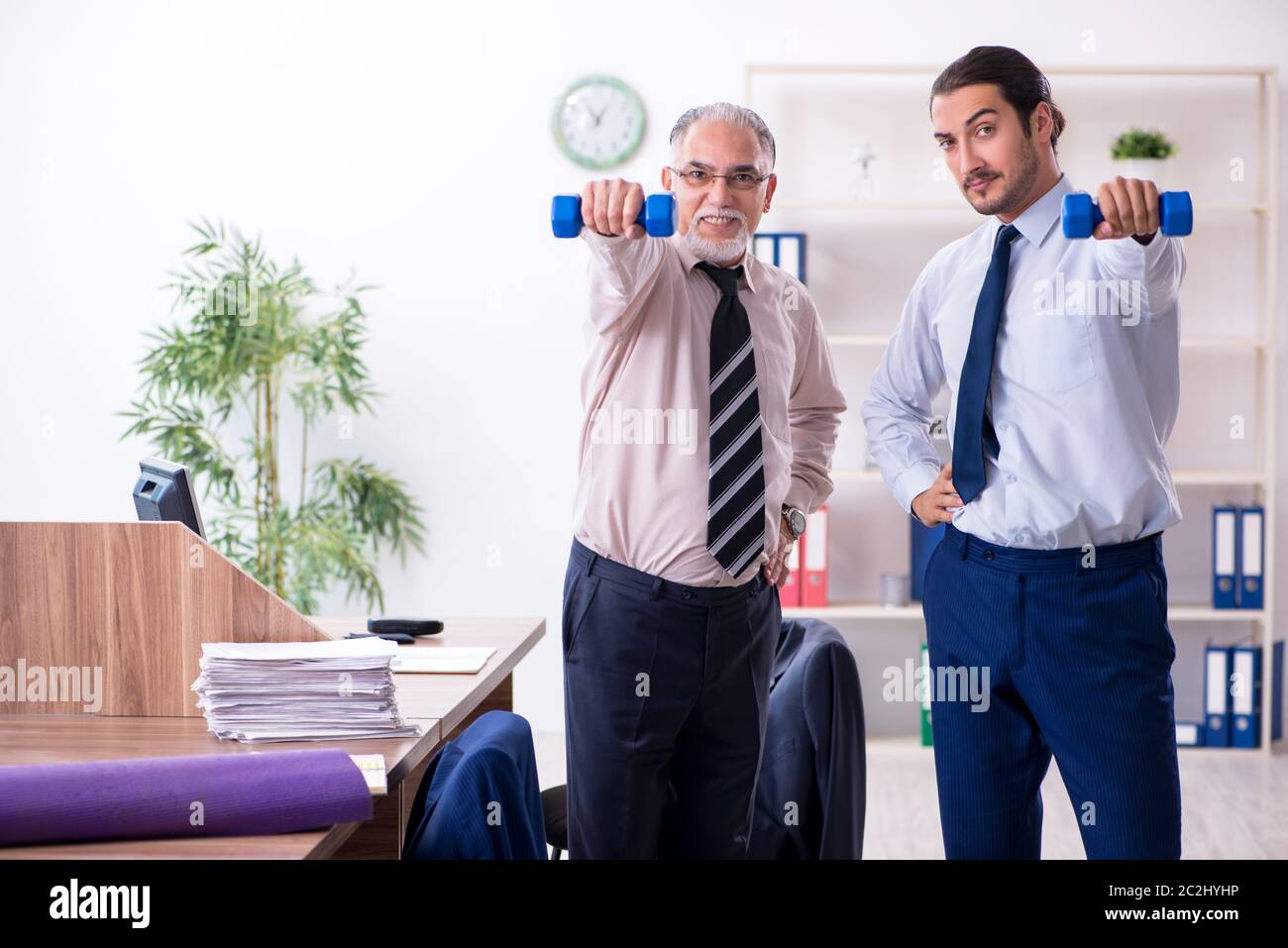 Two employees doing physical exercises at the workplace Stock Photo - Alamy