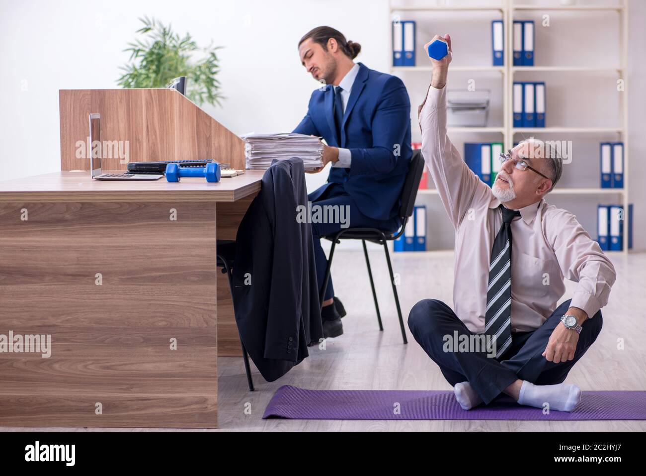Two employees doing physical exercises at the workplace Stock Photo - Alamy