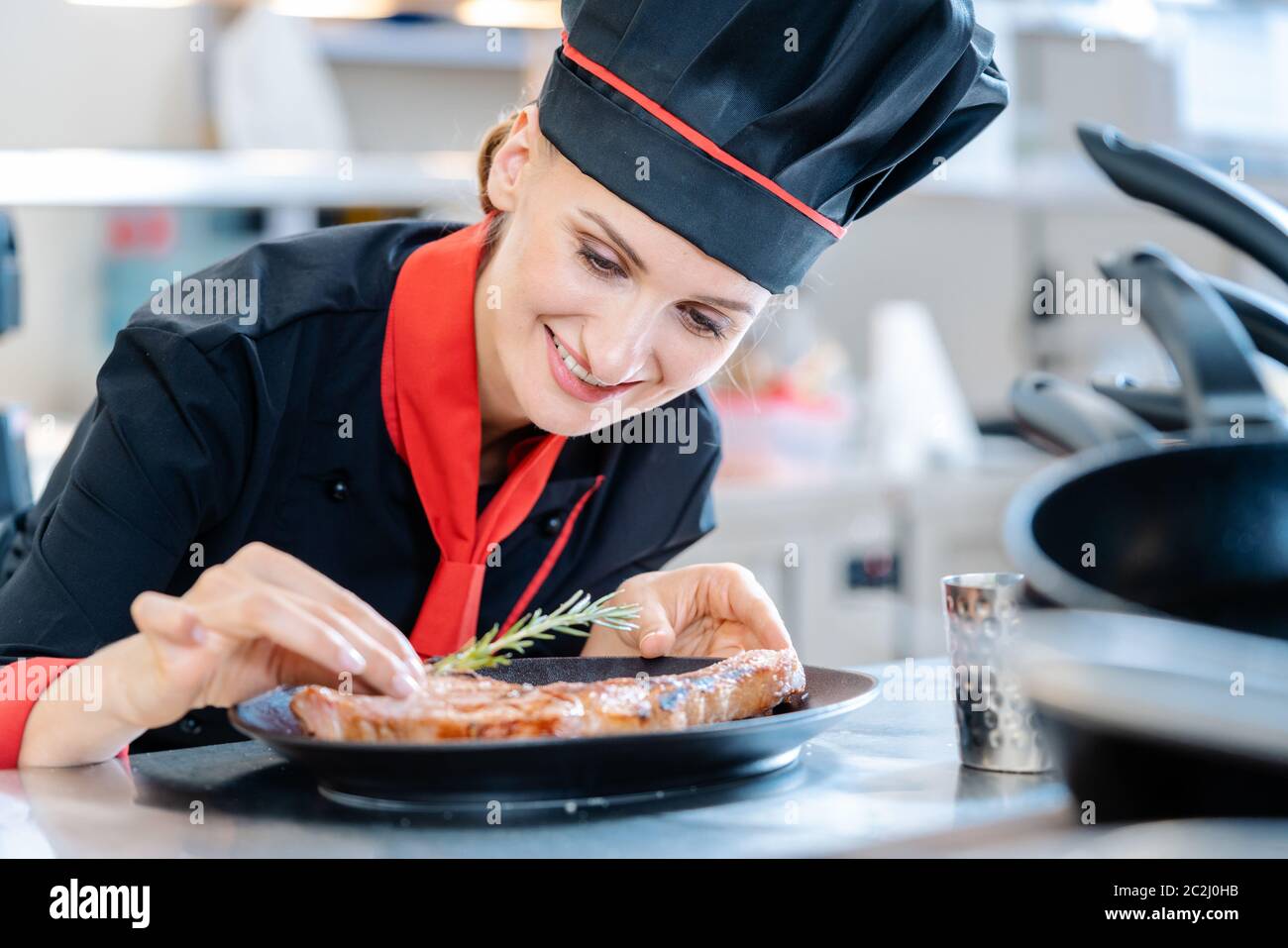A close up of a female chef putting rosemary on a cooked lamb steak ...