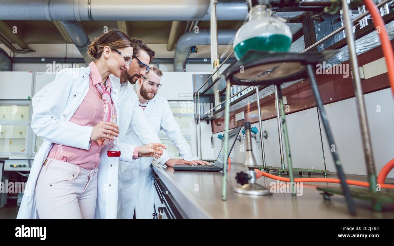 Three analytical chemists doing research in the lab, shot though the ...