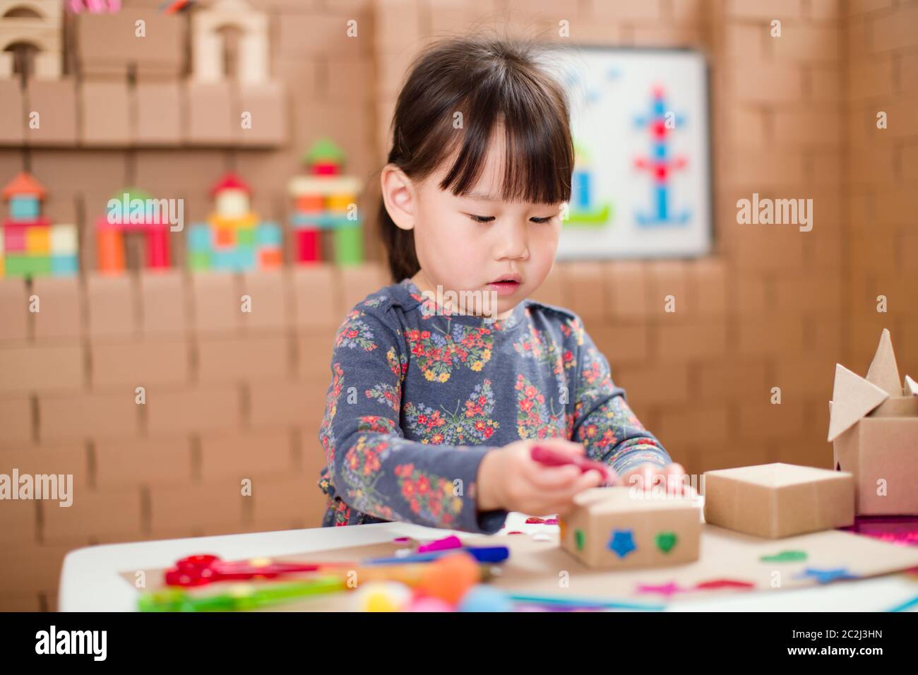 toddler girl making craft by using cardboard for homeschooling Stock ...
