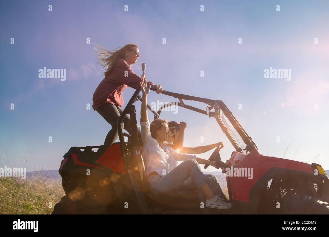 group of young people having fun while driving a off road buggy car ...