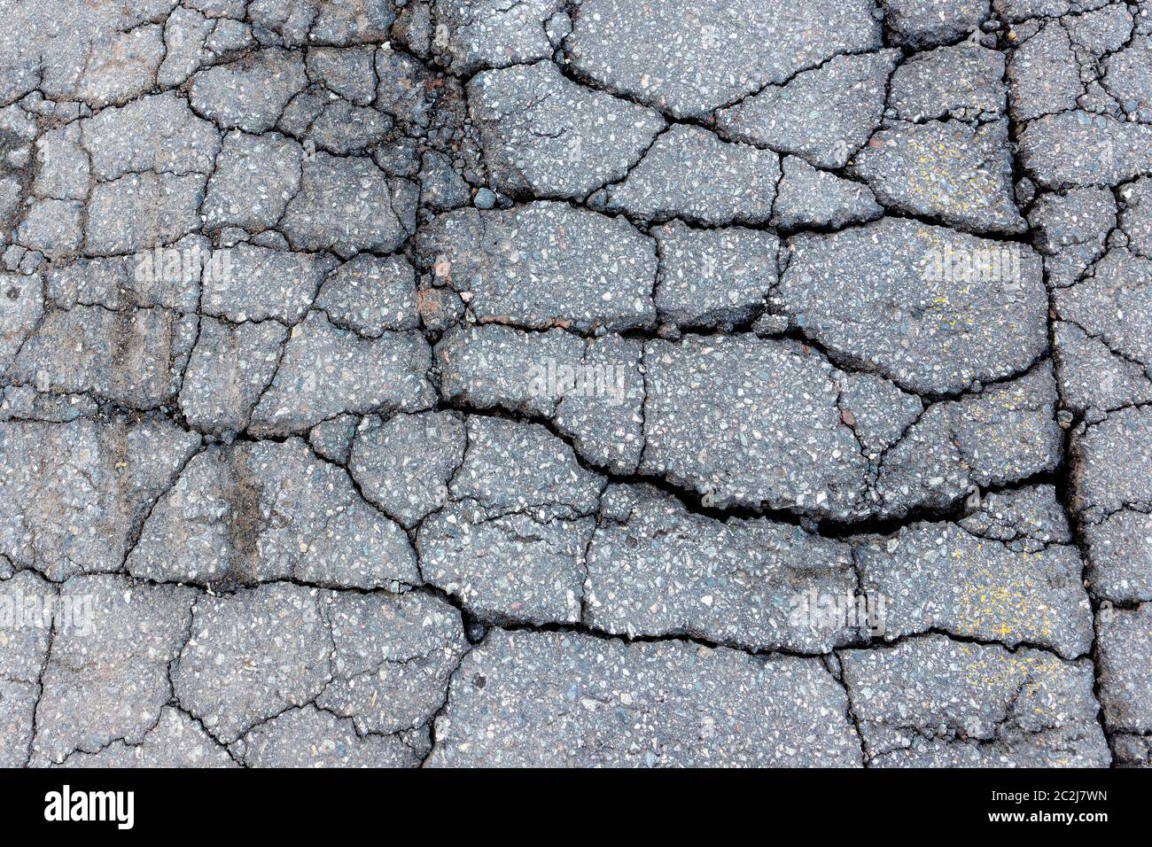 Cracked asphalt. A road composed of severely cracked asphalt. Closeup ...