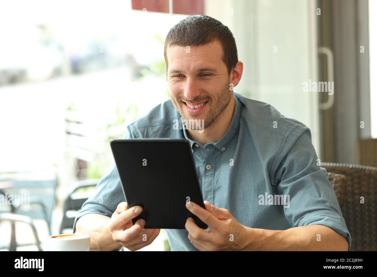 Happy man reading tablet content sitting in a coffee shop Stock Photo ...