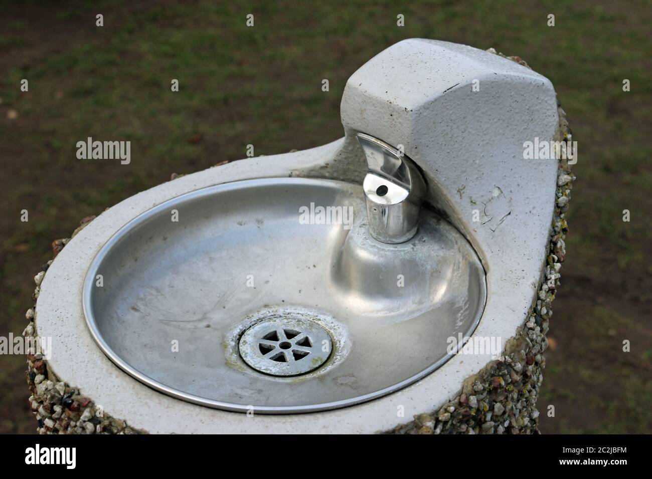 Metal park drinking fountain with bowl on a concrete plinth with a ...