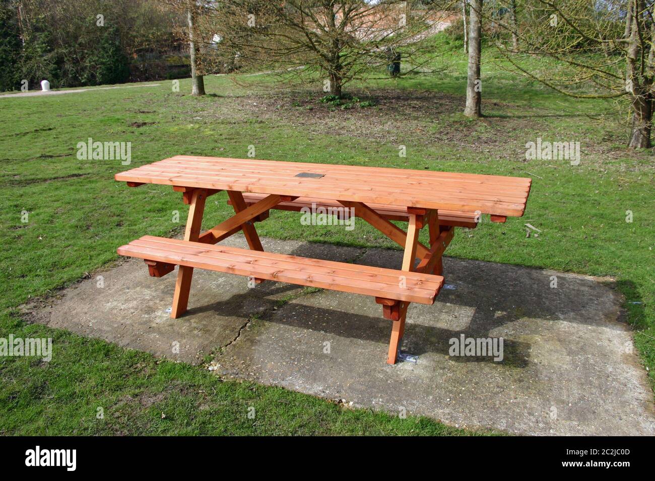 Wooden picnic table on concrete base in a grassed picnic site with a ...