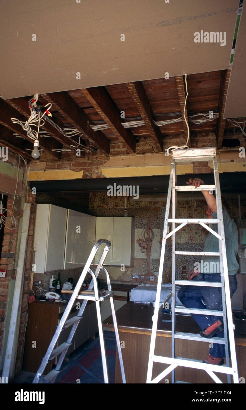 Kitchen Renovation Worker On Step Ladder Fixing Lights Stock Photo - Alamy