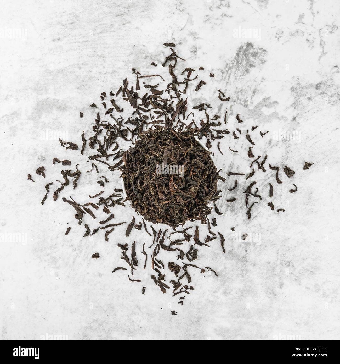 Dried tea is poured into a white ceramic cup on a marble table. View ...