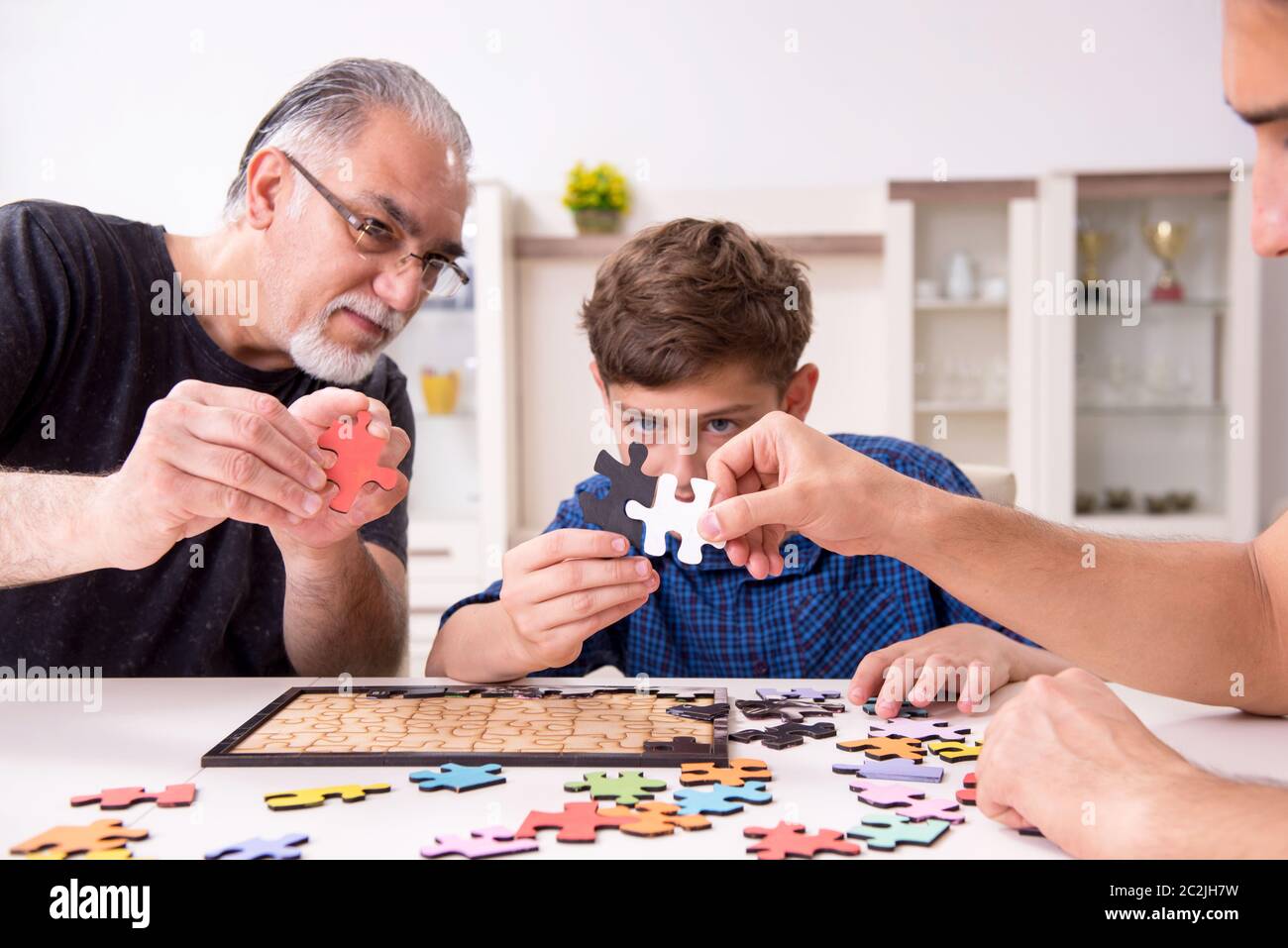 Three generations of family playing jigsaw puzzle Stock Photo - Alamy