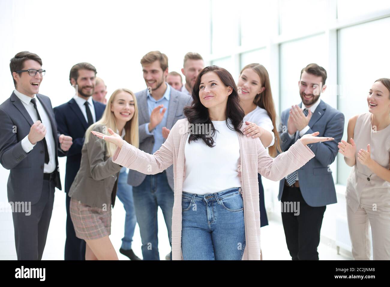 happy business lady standing in front of applauding team of employees ...