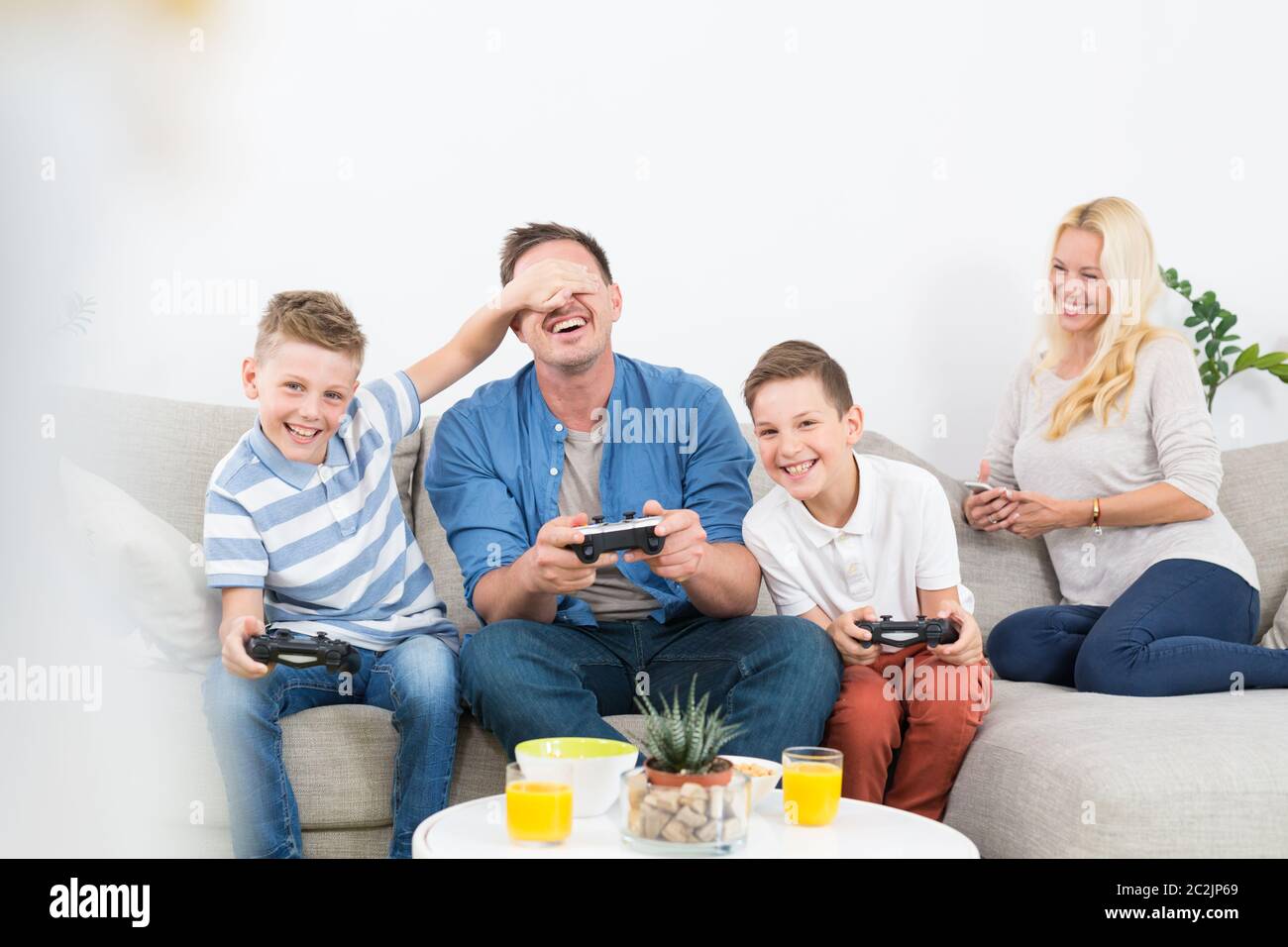 Happy young family playing videogame console on TV. Spending quality ...