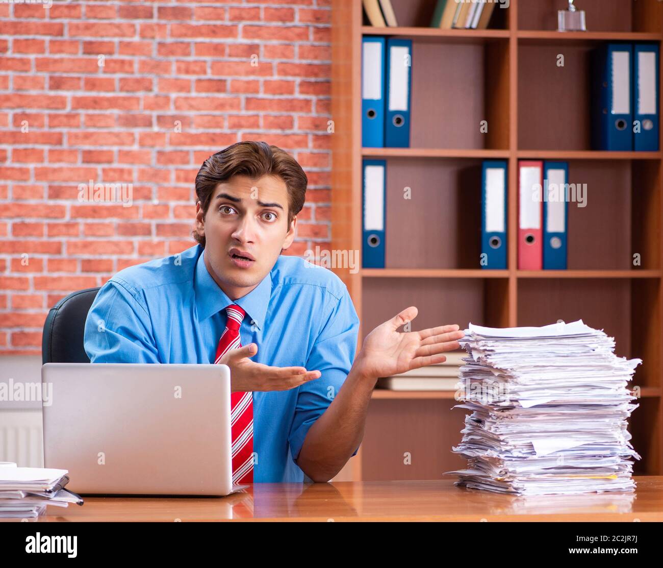 The young employee with excessive work sitting at the office Stock ...