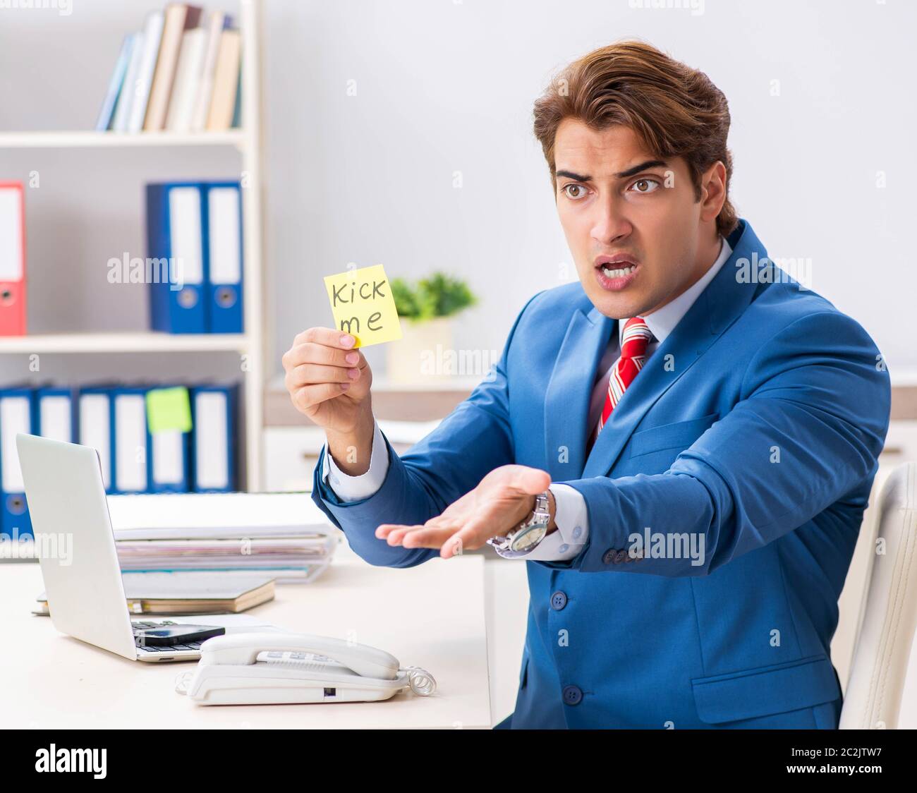 The office prank with kick me message on sticky note Stock Photo - Alamy