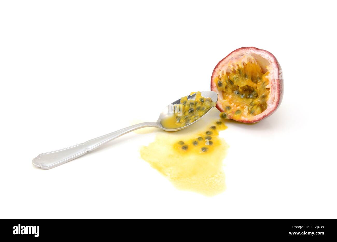 Scooping out pulp from half a passion fruit with a spoon, spilled seeds ...