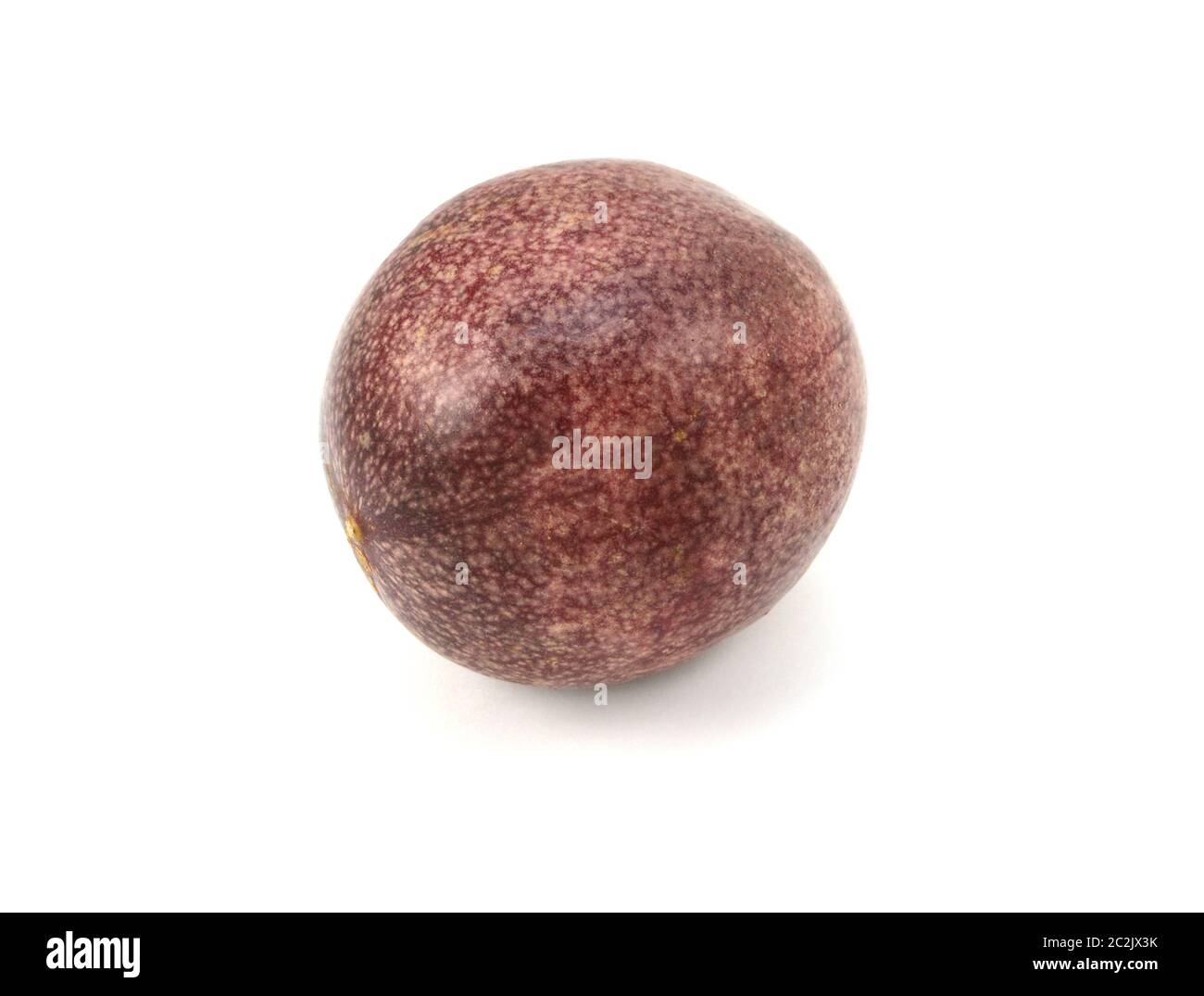 Whole passion fruit with speckled deep purple skin, on a white ...