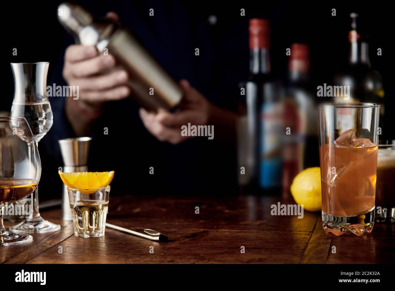 Barman mixing cocktails in a martini shaker behind a bar counter with ...
