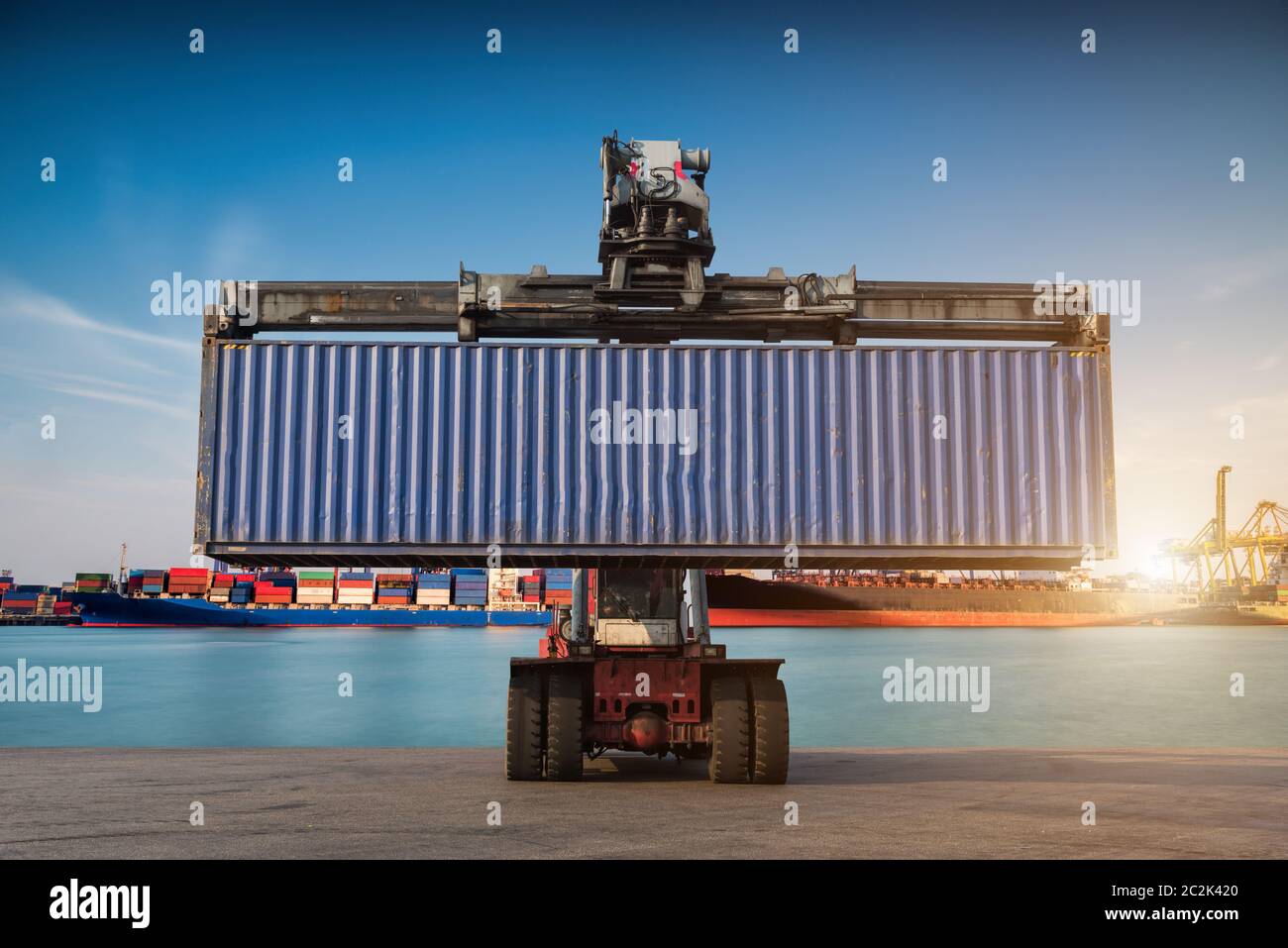 Forklift handling container box loading at port cargo at sunset Stock ...