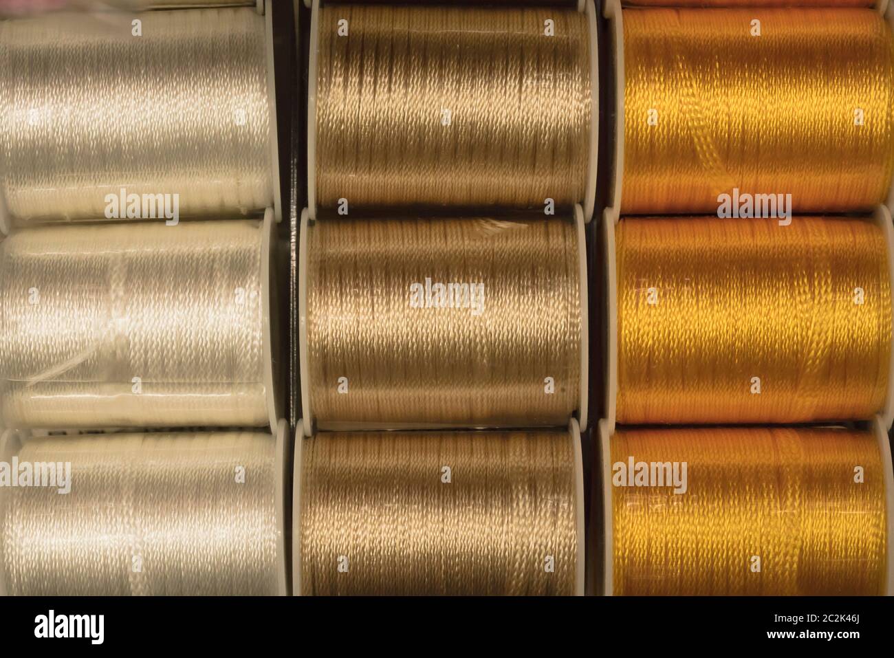 Cutout texture closeup on coils of colored sewing threads white,gold ...