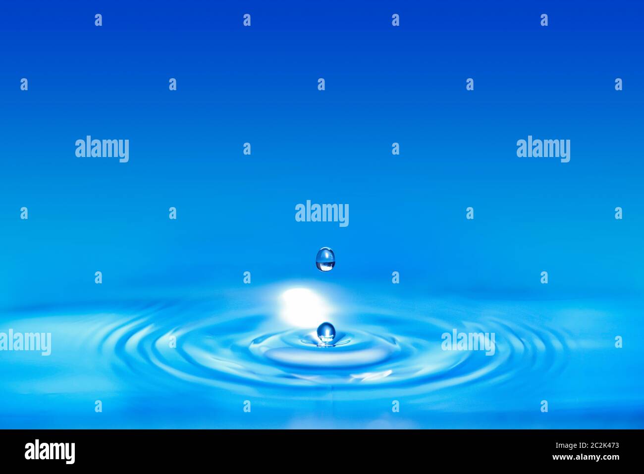 Closeup on double drop of water falling in a blue liquid and create ...