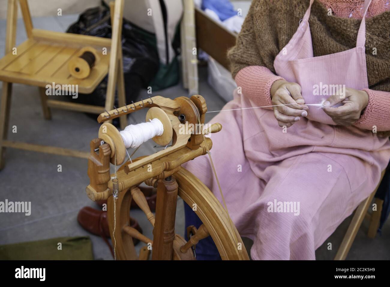 Spinning with a wooden spinning wheel, handicraft detail, thread ...