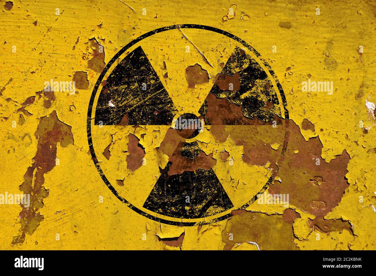 Black radioactive hazard warning sign painted over grunge yellow metal ...