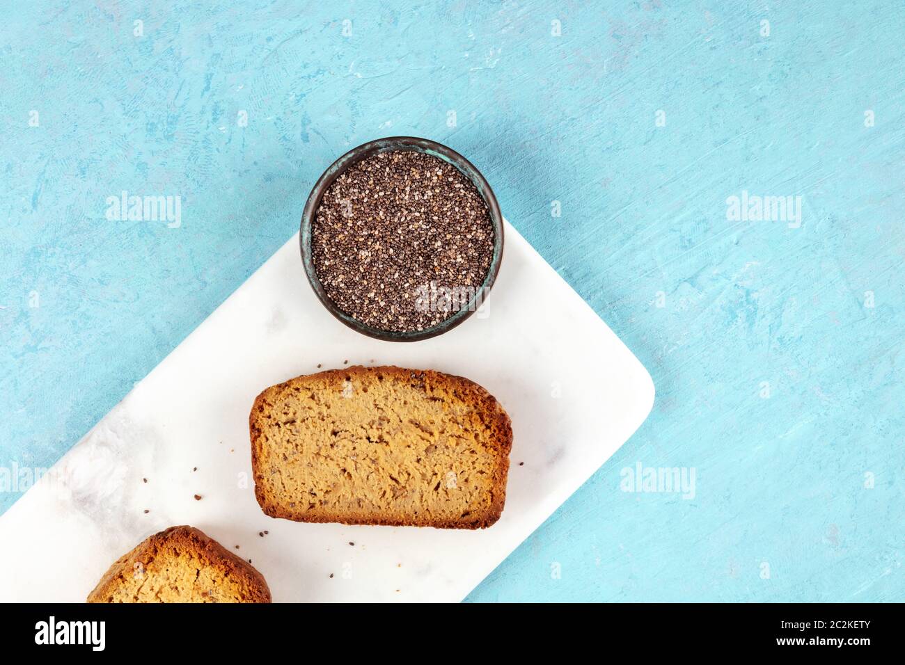Chia seed cake, shot from above on a marble cutting board and a blue ...