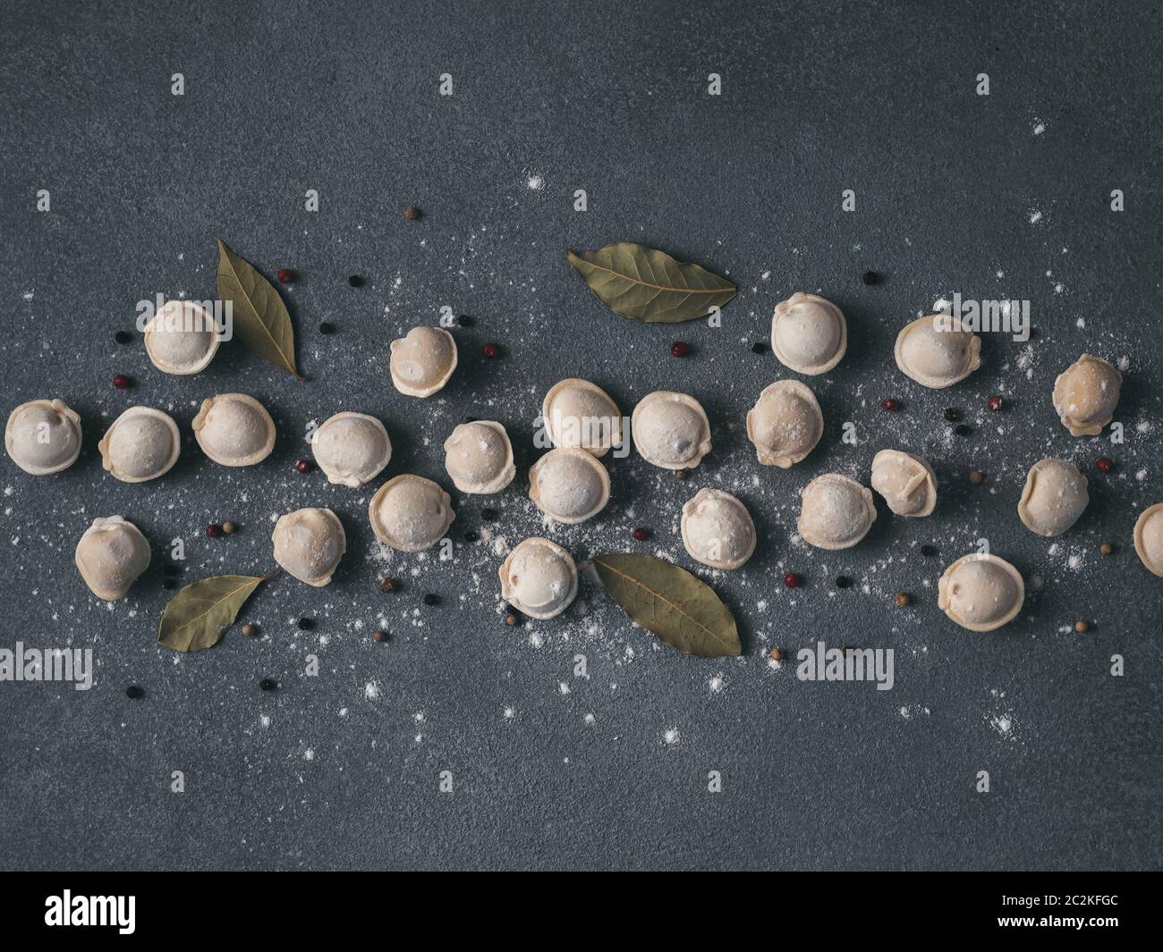 Pattern of frozen uncooked russian pelmeni with peppercorns and bay ...