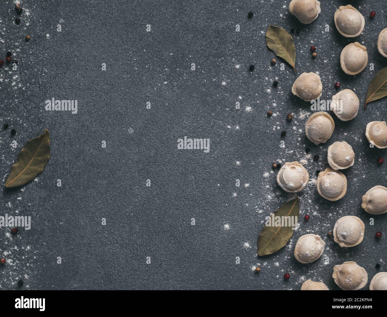 Pattern of frozen uncooked russian pelmeni with peppercorns and bay ...