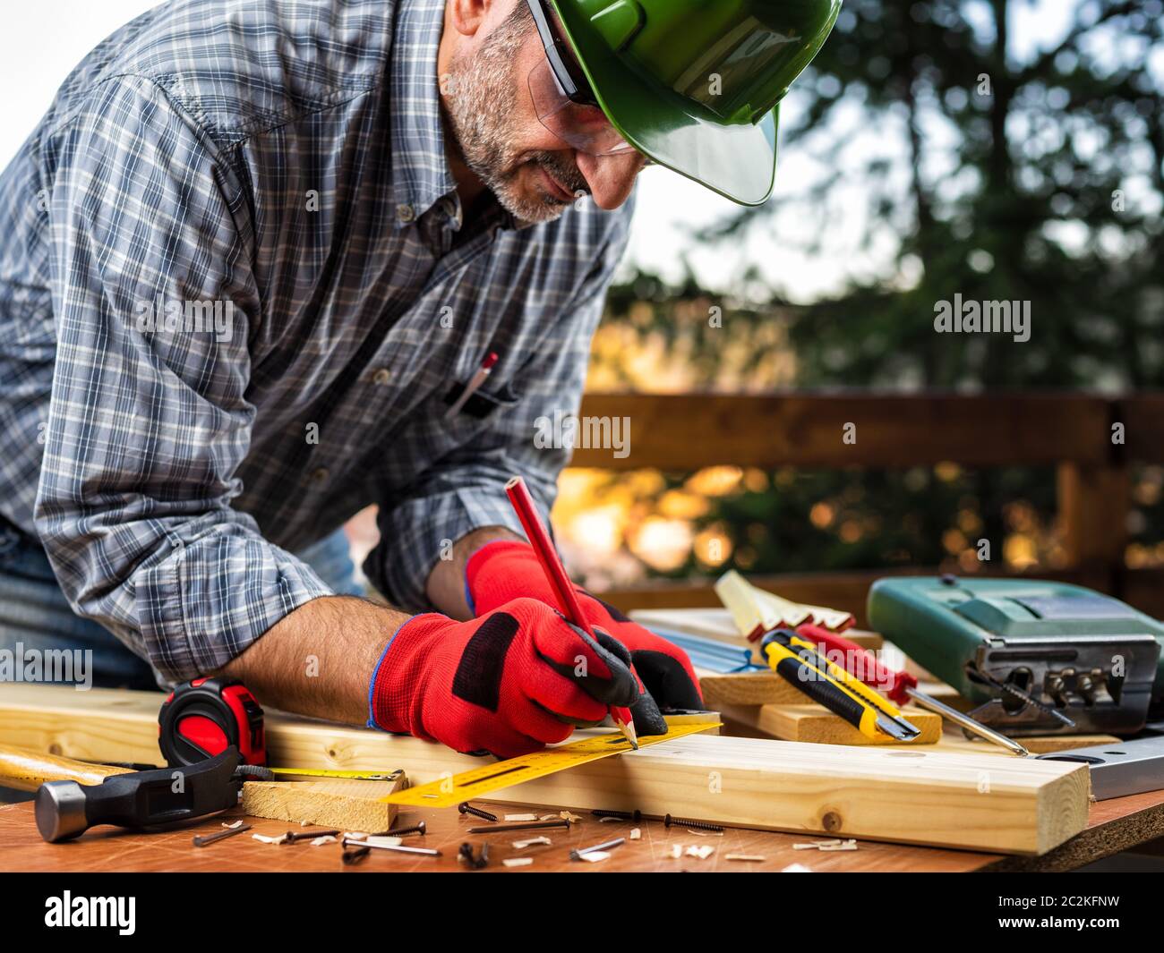 Adult carpenter craftsman wearing helmet and protective gloves, with a ...