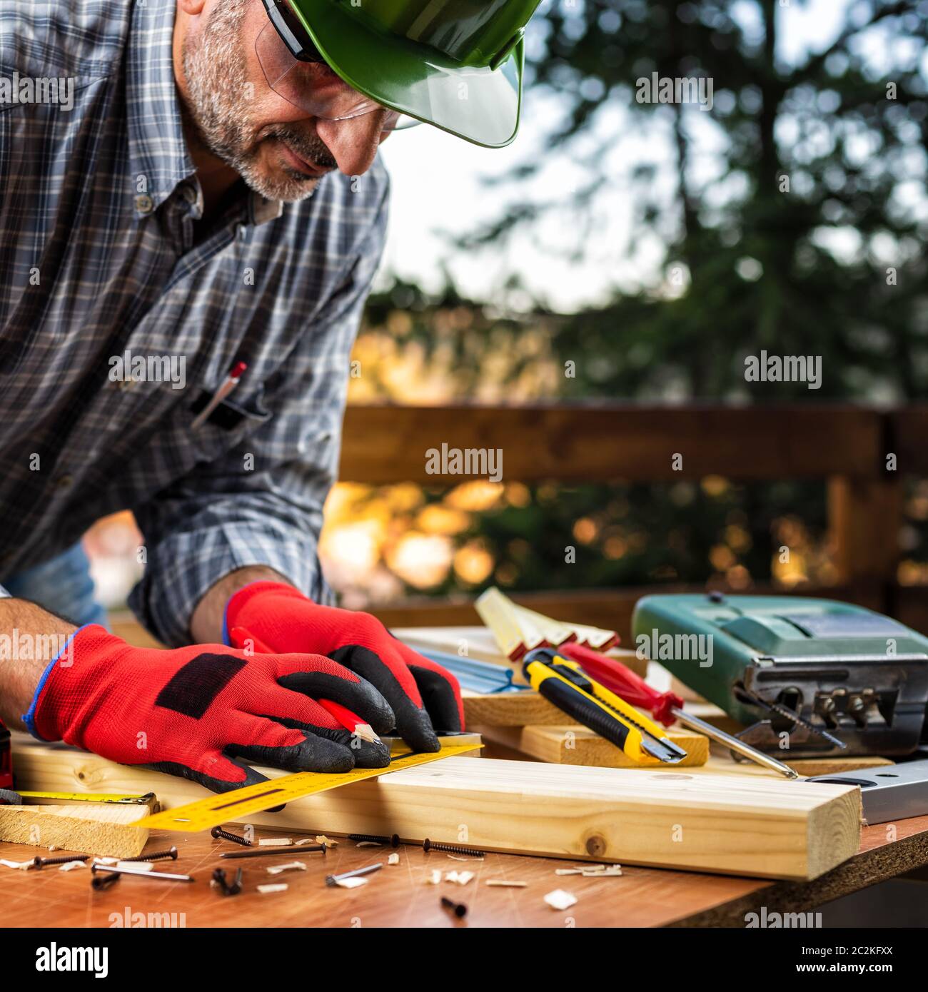 Adult carpenter craftsman wearing helmet and protective gloves, with a ...
