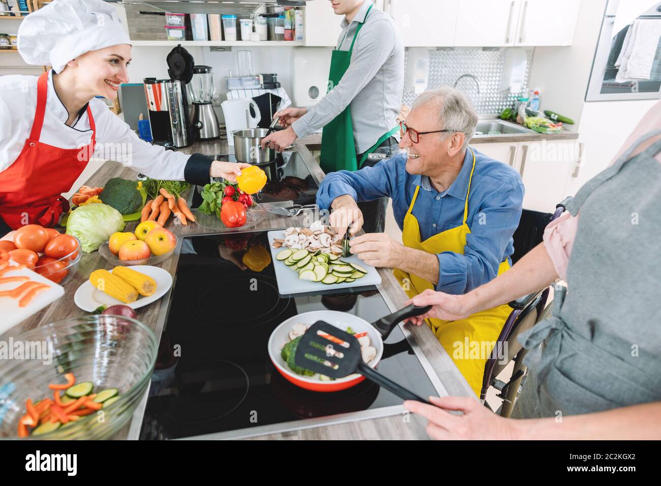 Group of men and women learning cooking in training kitchen with ...