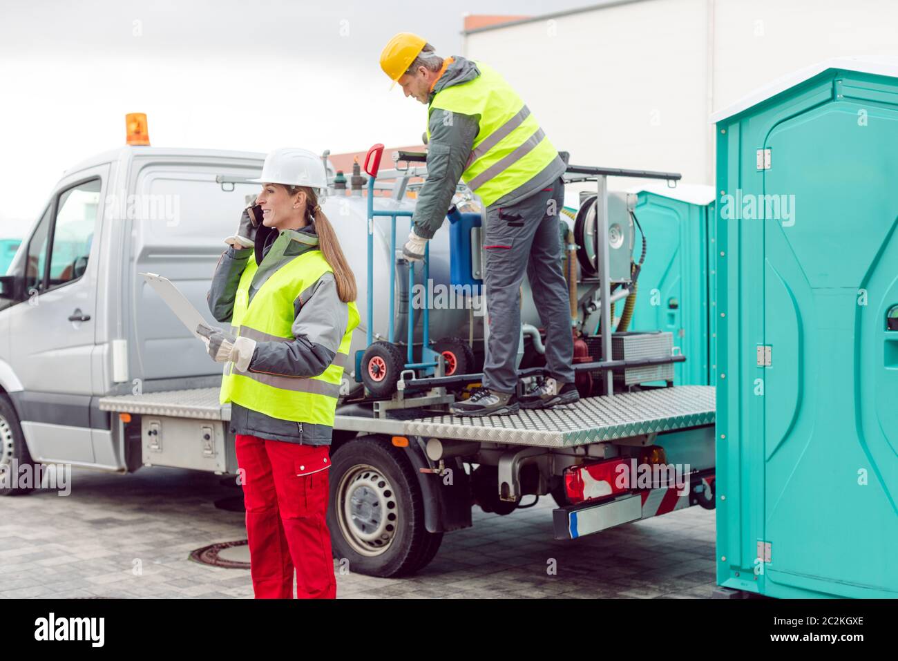 Workers taking care of a delivery of mobile rental toilets by truck ...