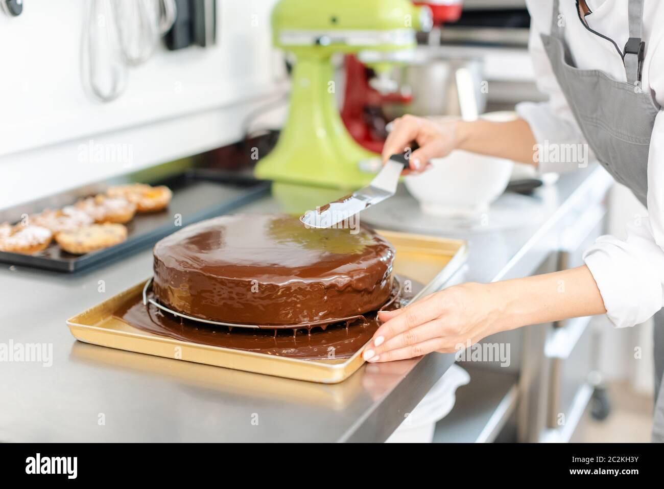 Patissier pouring liquid chocolate on a cake in her workshop Stock ...
