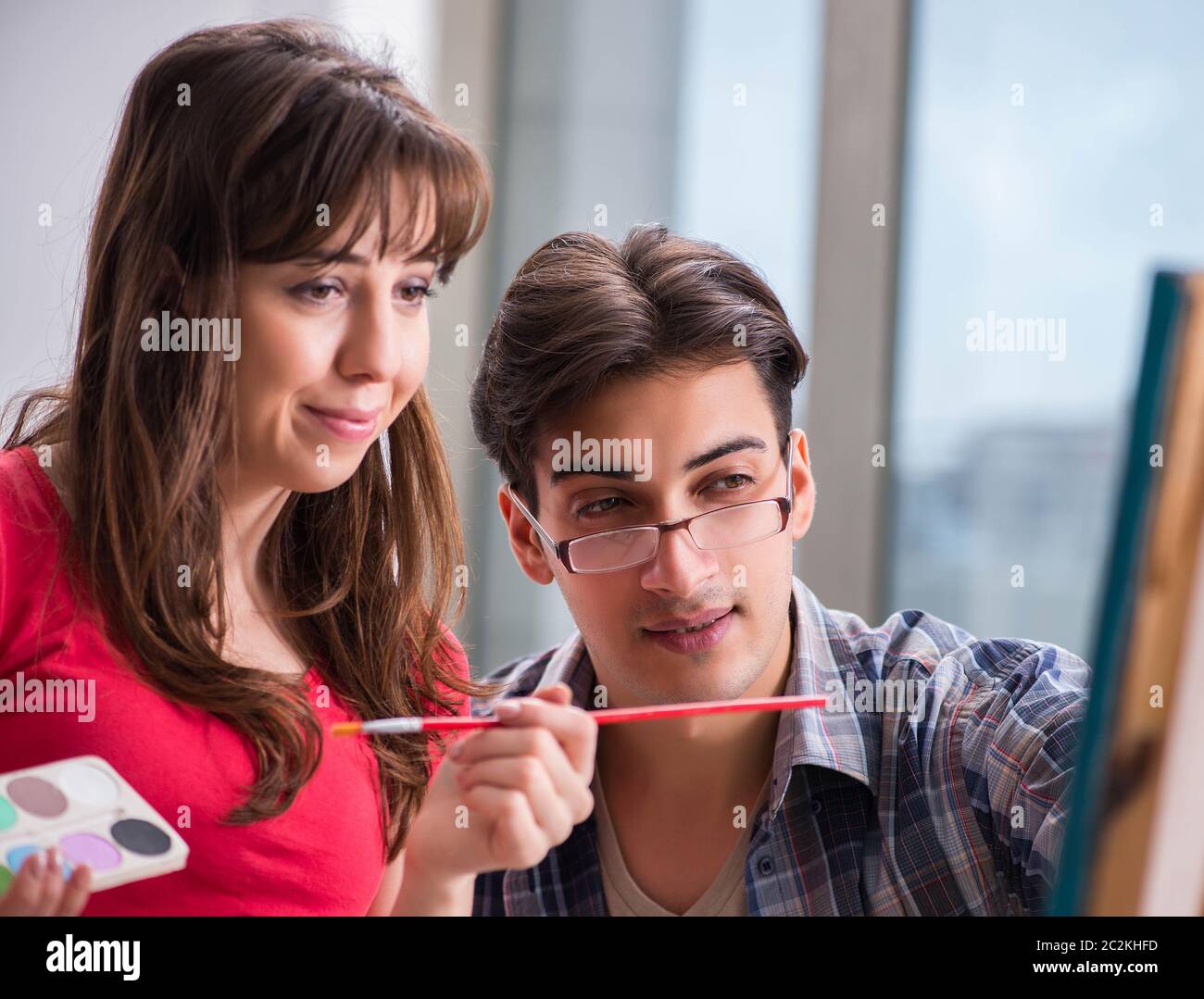 The artist coaching student in painting class in studio Stock Photo - Alamy