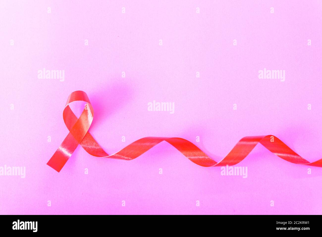 Red Ribbon Support HIV, AIDS on pink background and copy space for use ...